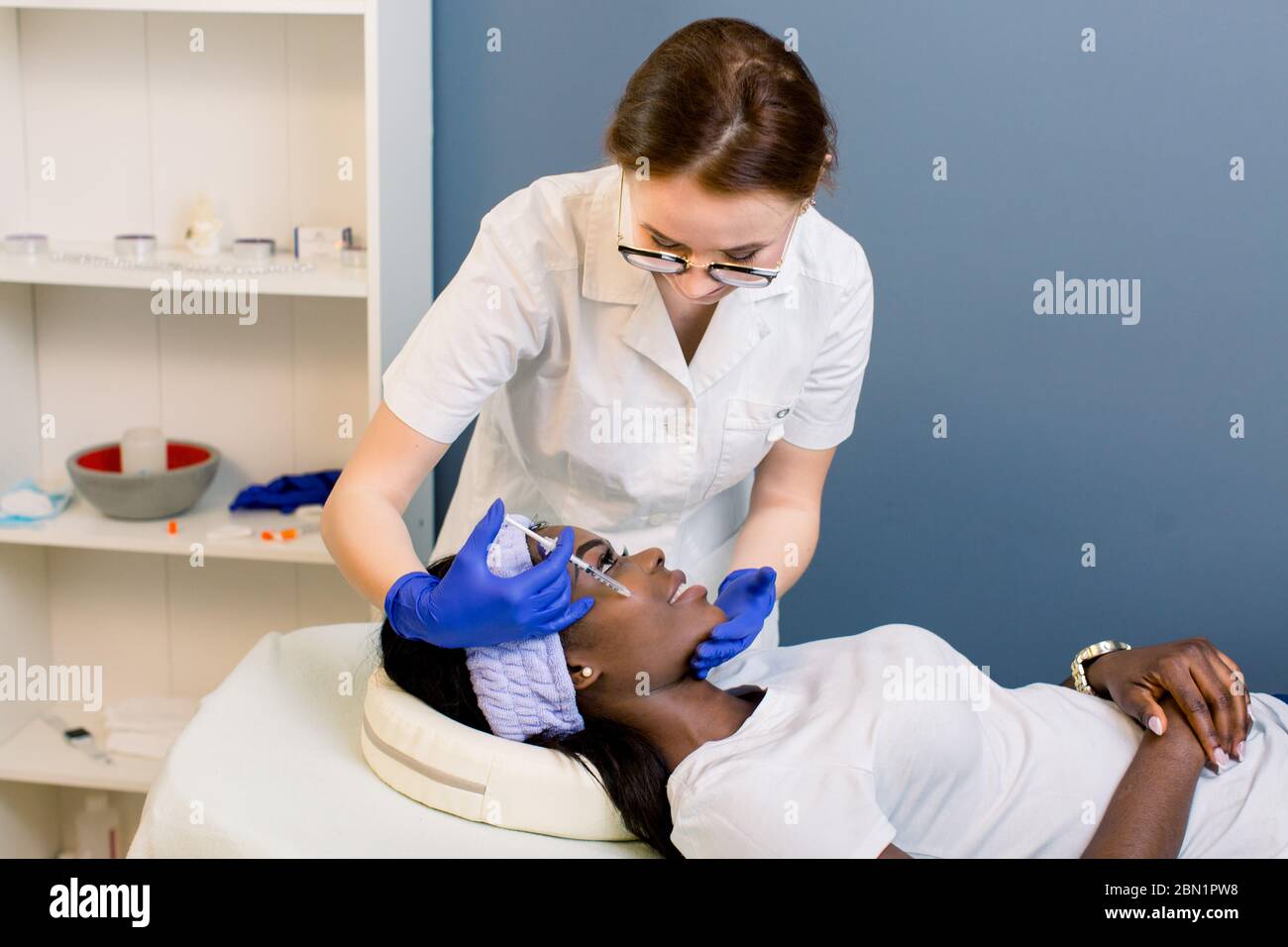 Young female Caucasian doctor performing a botox injection to the ...
