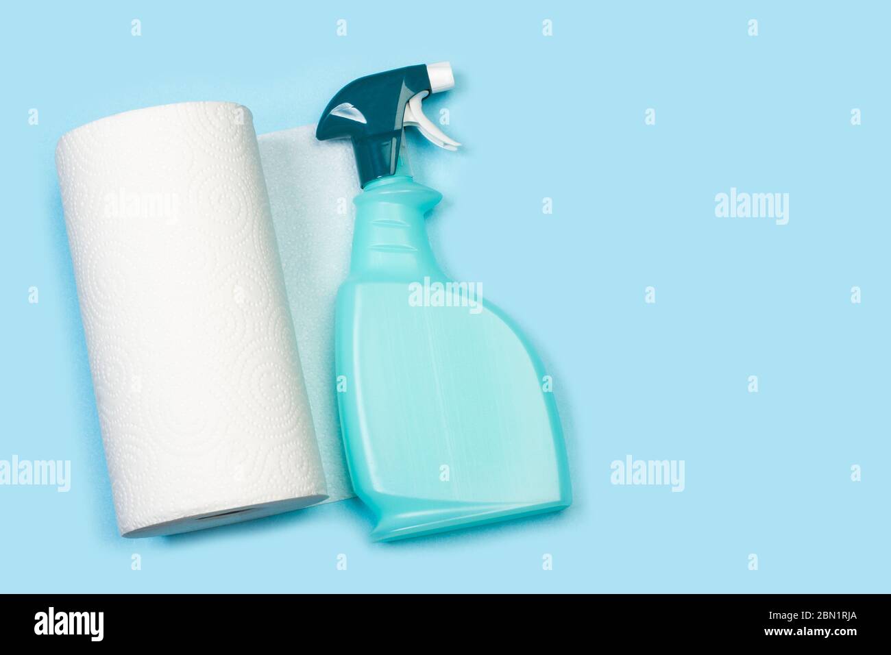 A kitchen paper roll and a cleaning sprayer bottle on a light blue ...