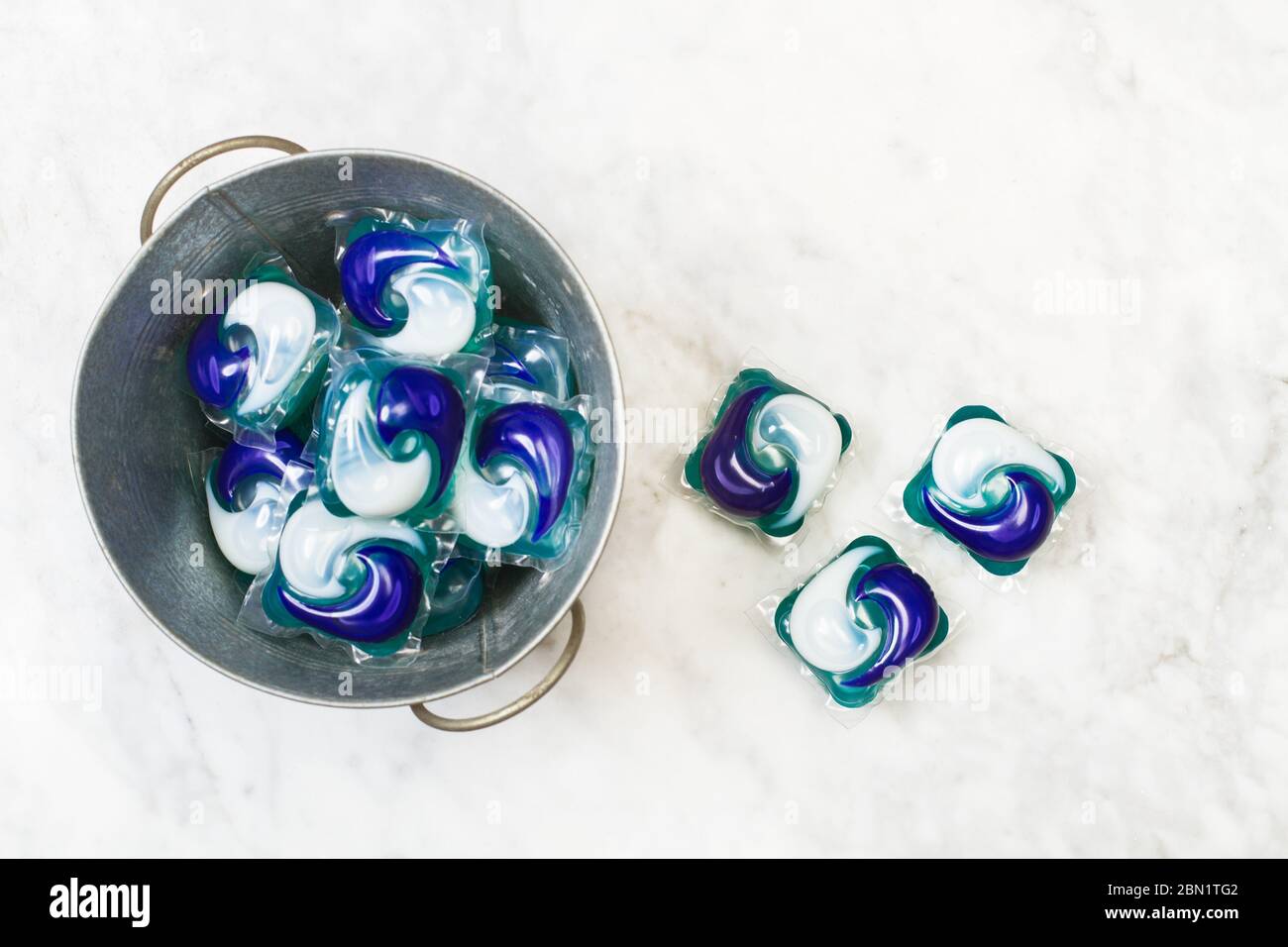 Washing machine detergent pods in a galvanized bucket and on a marble ...