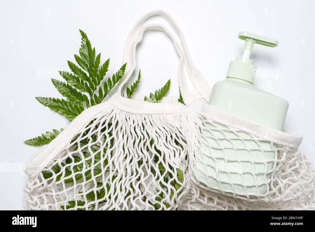 Green container for shampoo, conditioner or liquid soap in eco bag with ...