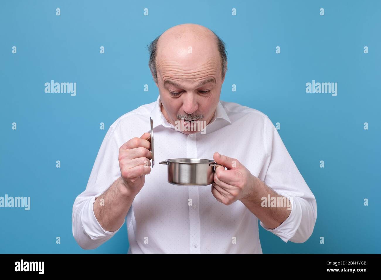 Senior funny caucasain man looking into a small empty pan Stock Photo ...