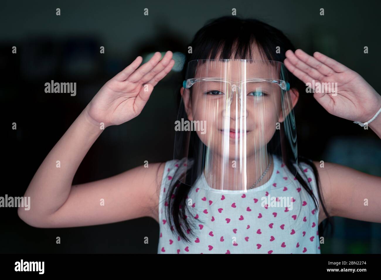 Happy little child girl with a plastic face shield for a virus ...