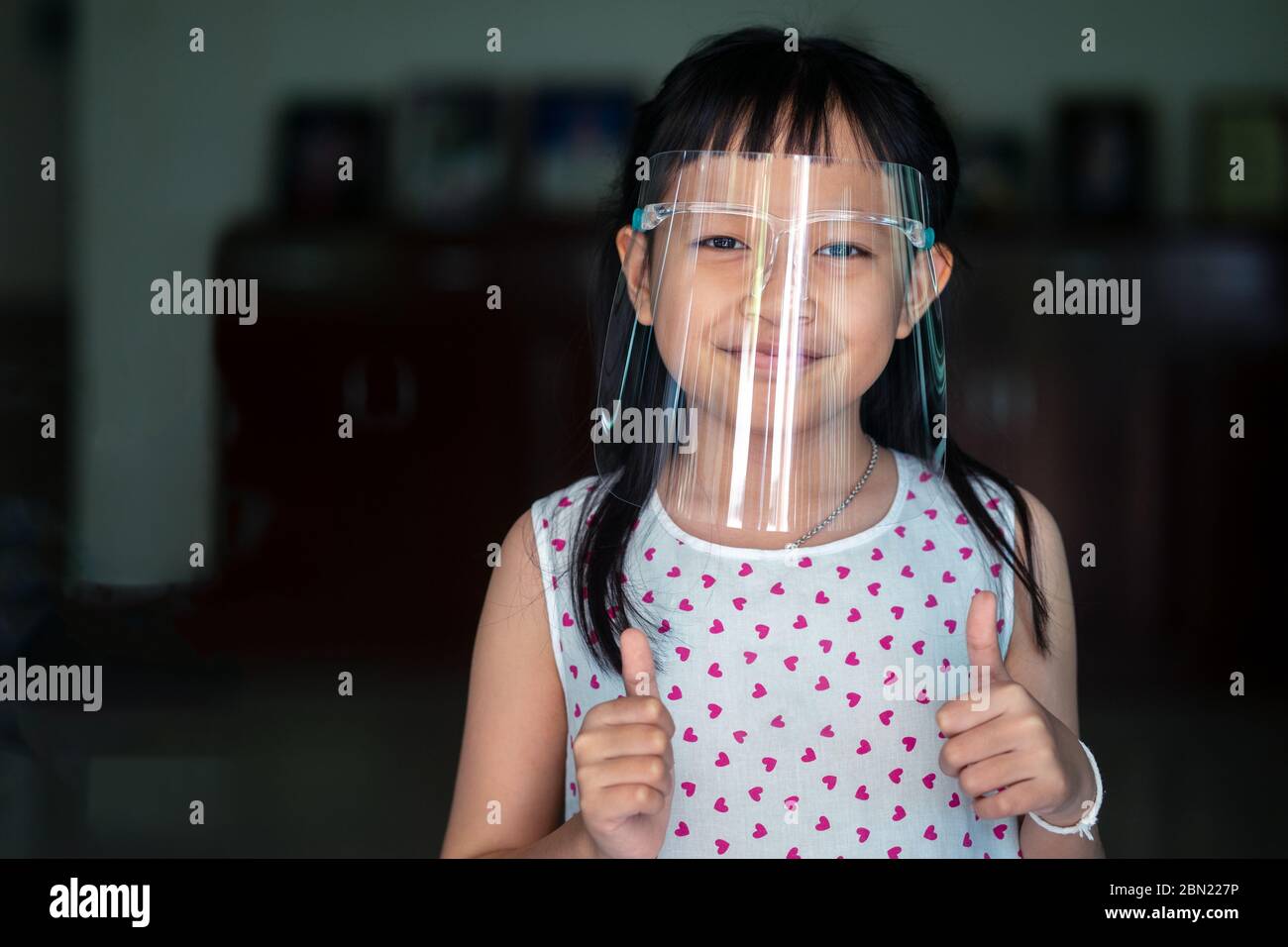 Happy little child girl with a plastic face shield for a virus ...