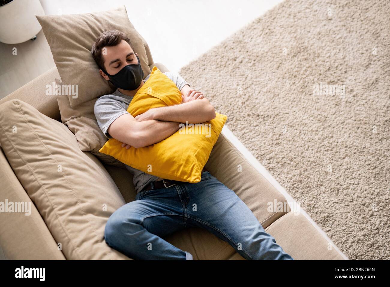 Above view of young man in facial mask embracing pillow and sleeping on ...