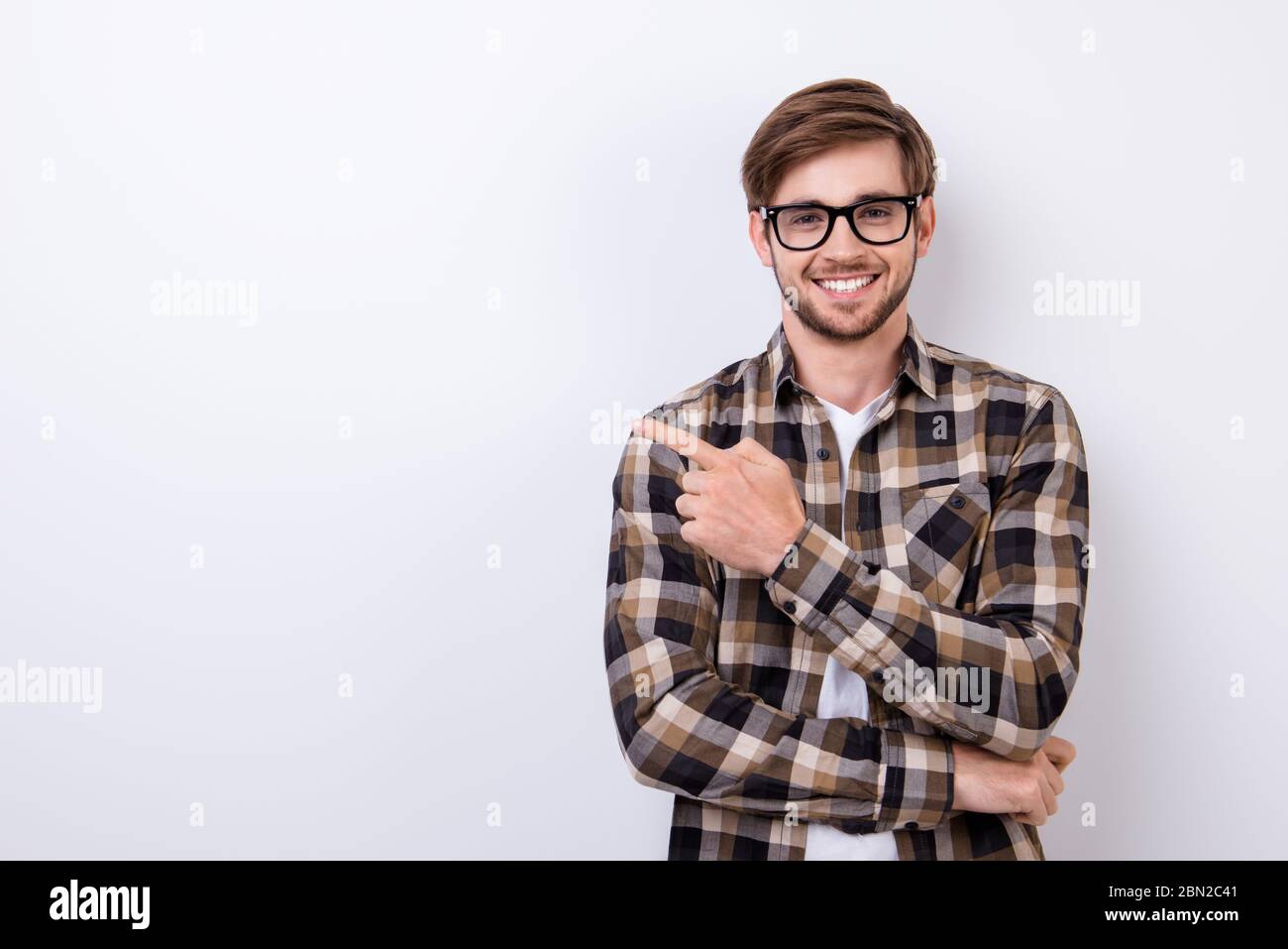 Smiling young nerdy bearded stylish student is standing on pure ...