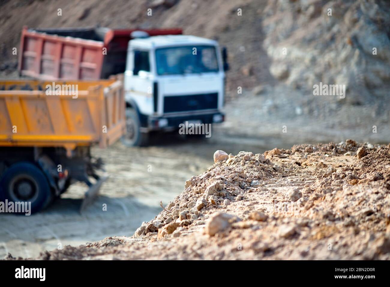 Pile of ore rocks over out of focus background with two heavy multi-ton ...