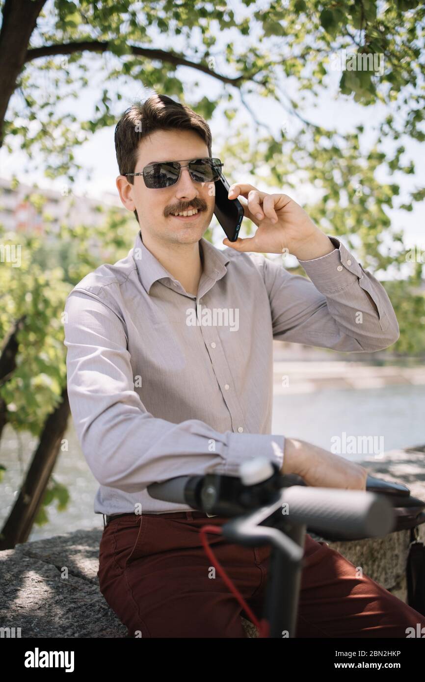 Happy guy having conversation while sitting under tree. Man with ...
