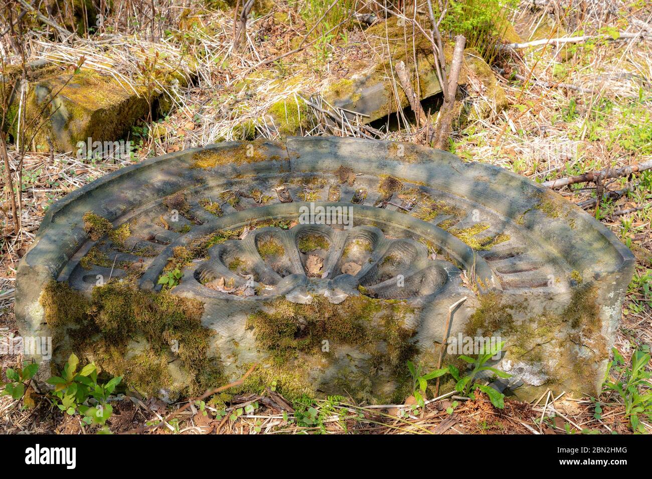 A semi circular stone carving resting amid ruins in the shadows on a ...