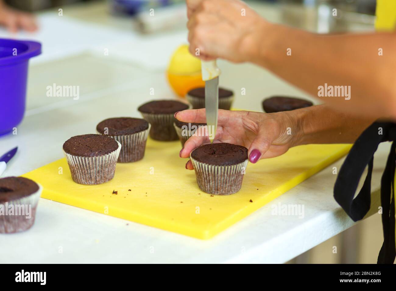 The process of making chocolate cupcakes with sweet cream. Creation of cakes by professional ...