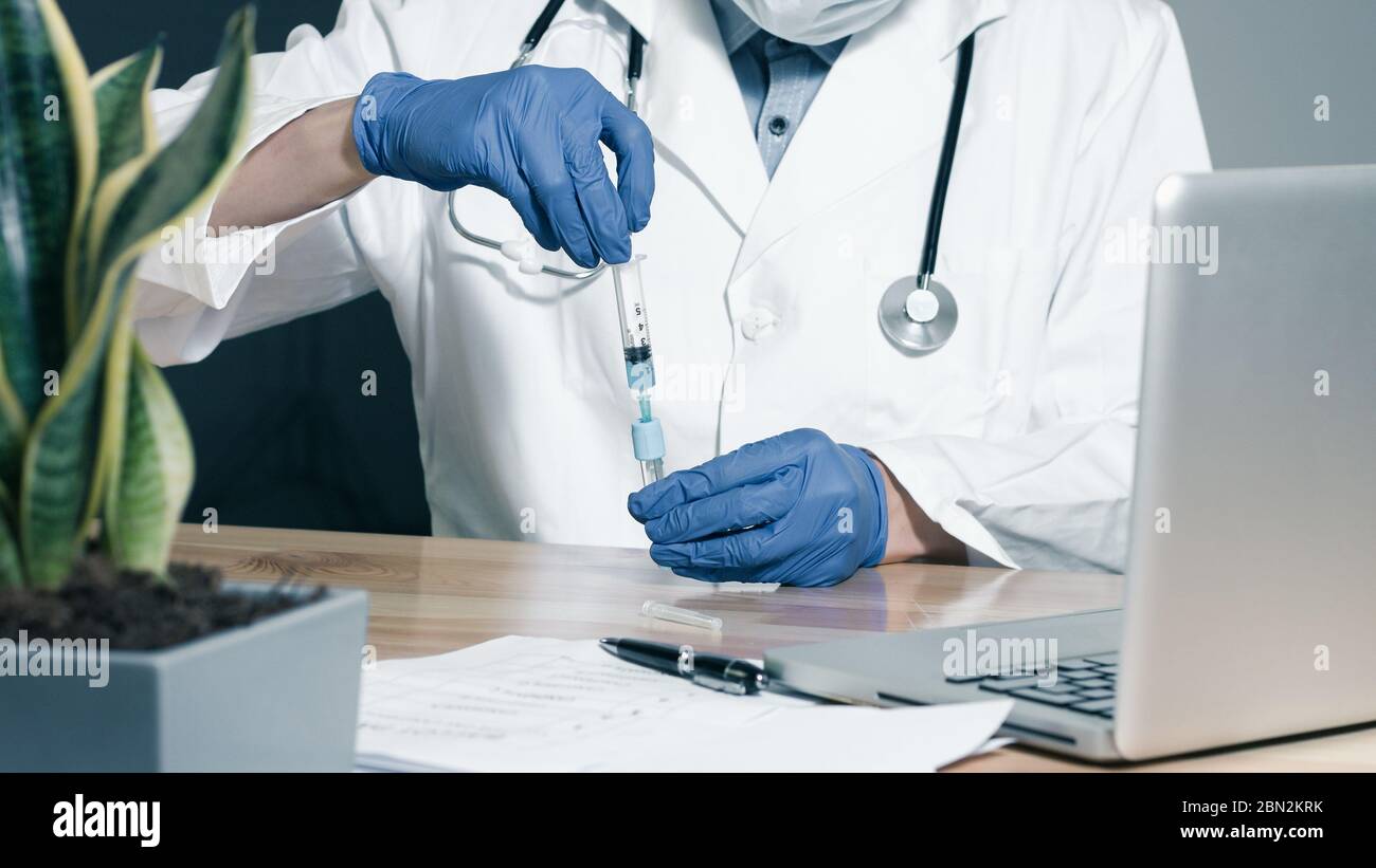Doctor preparing vaccine syringe for injection and looking at needle ...