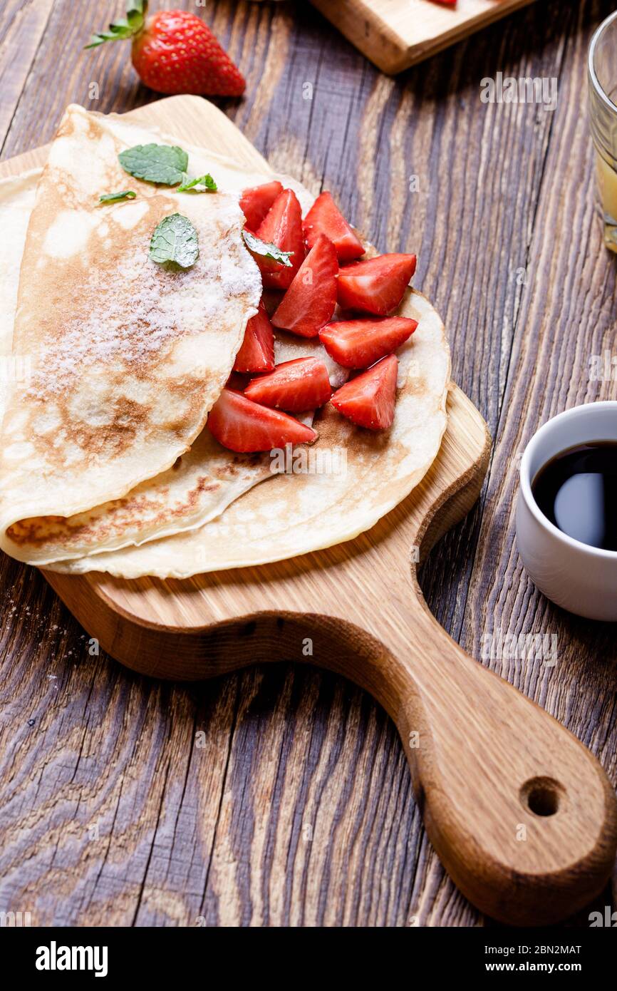 Crepes with fresh strawberries on wooden cutting board, summer dessert ...
