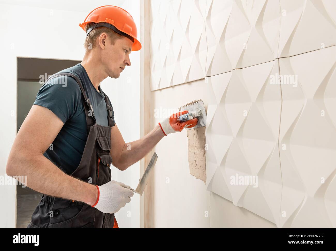 Installation of gypsum 3D panel. The worker is applying adhesive to the ...