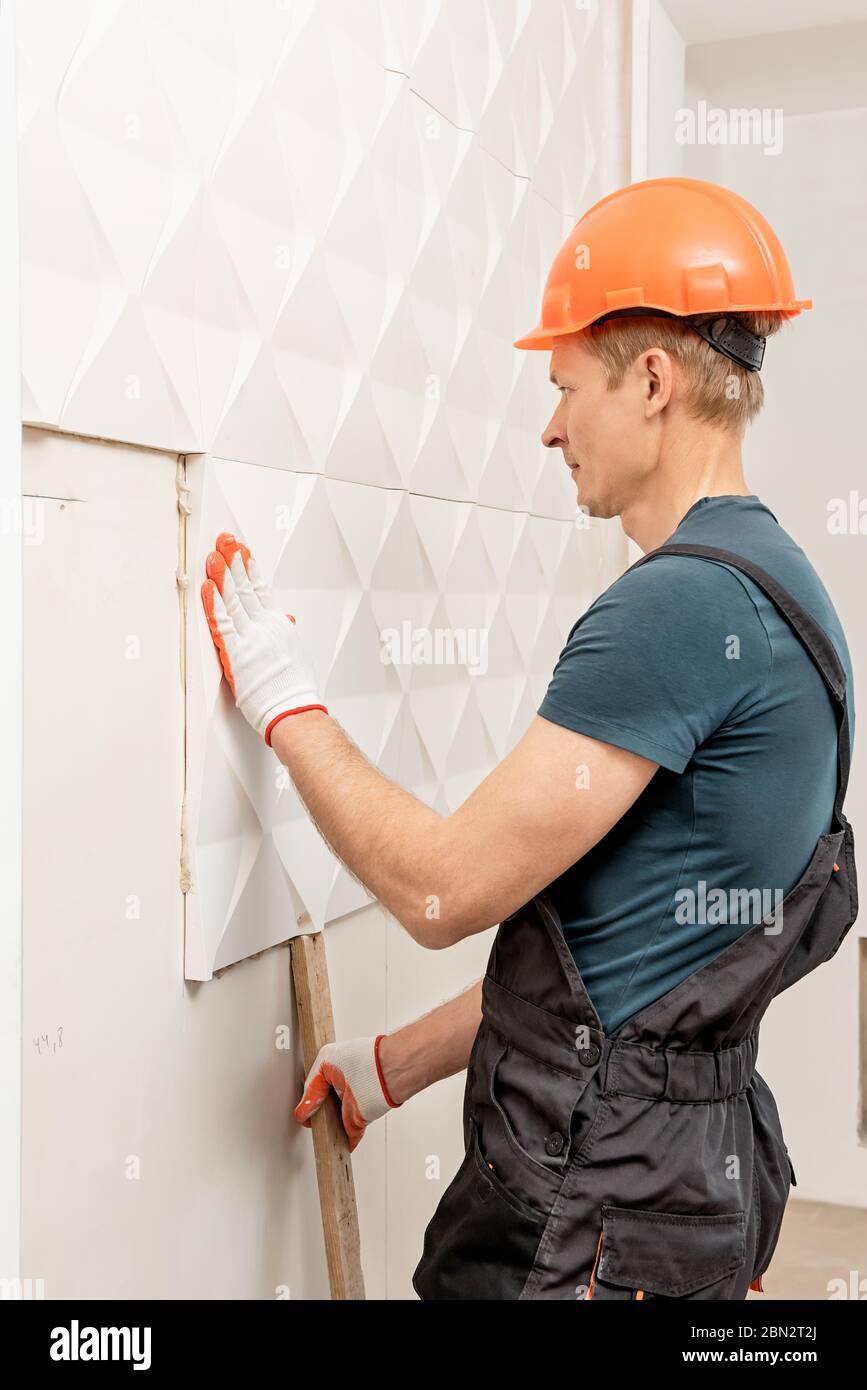 Installation of gypsum 3D panel. The worker is attaching the gypsum ...