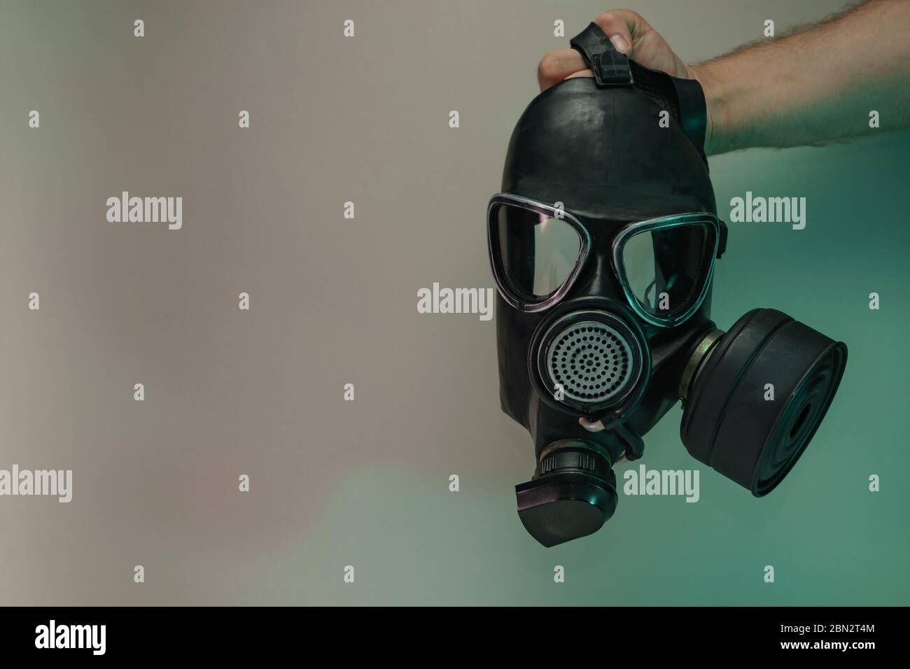 Hand hold black old gas mask in the color light. Beautiful old minimal ...