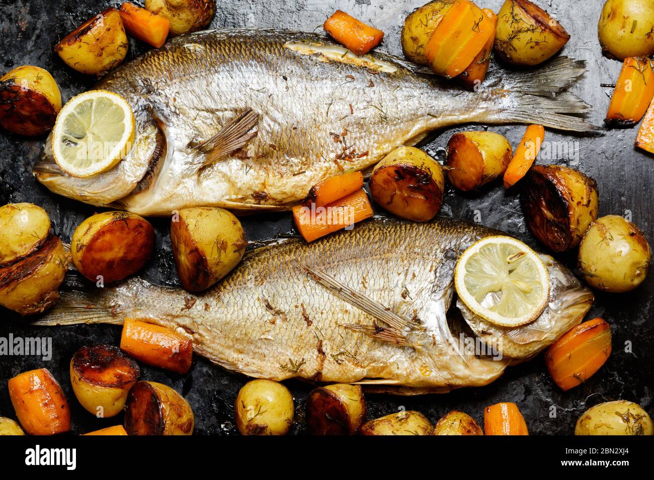 Baked Dorado fish with patatoes and carrot Stock Photo - Alamy