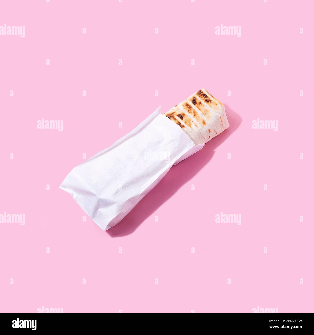 Gyro pita or shawarma with paper wrap on pastel pink background in pop ...