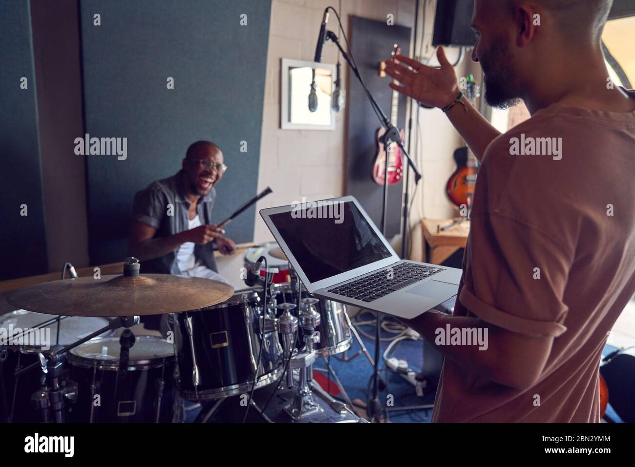 Happy musicians with drums and laptop in recording studio Stock Photo ...