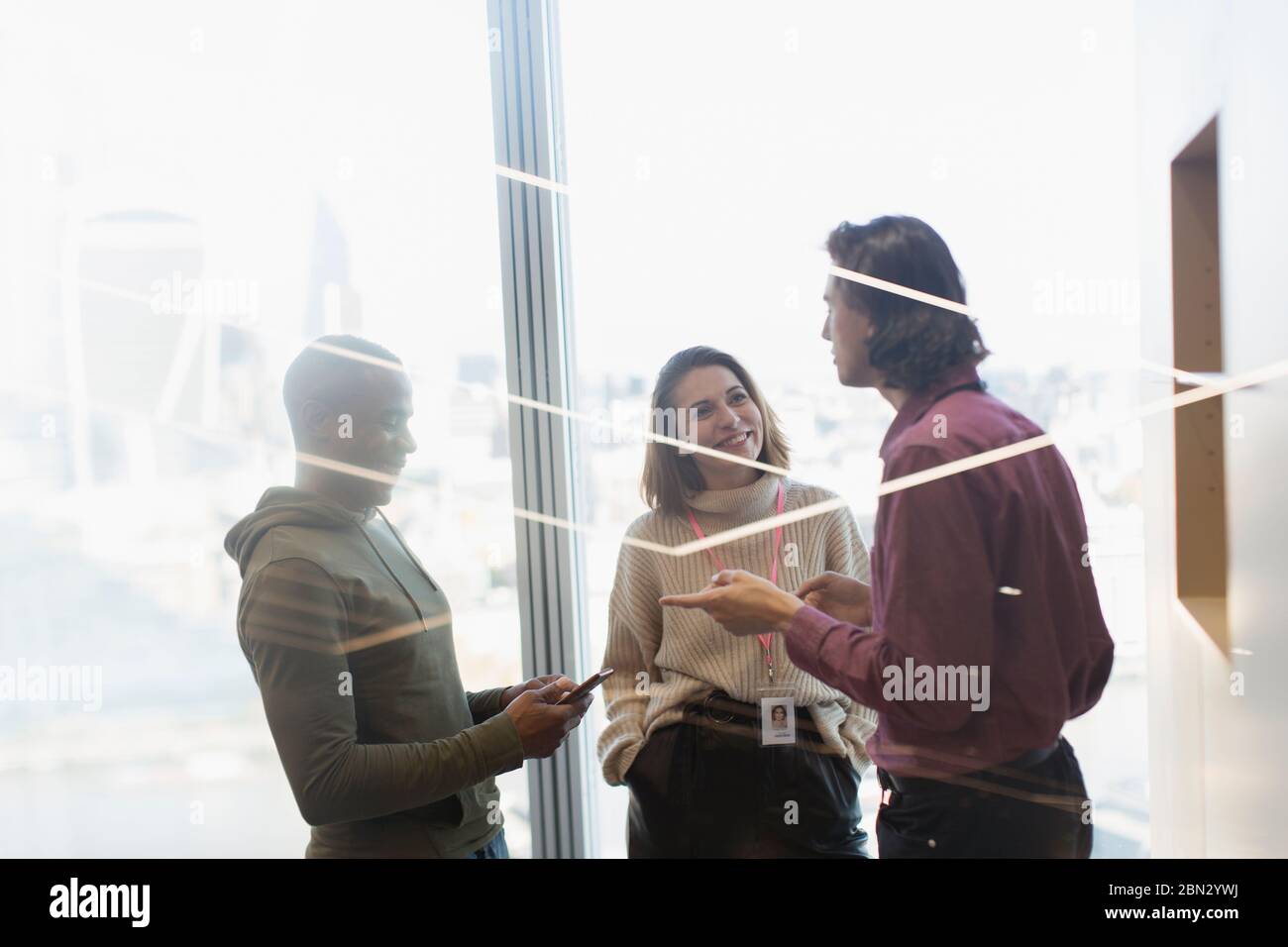 Business people talking at window in office Stock Photo - Alamy