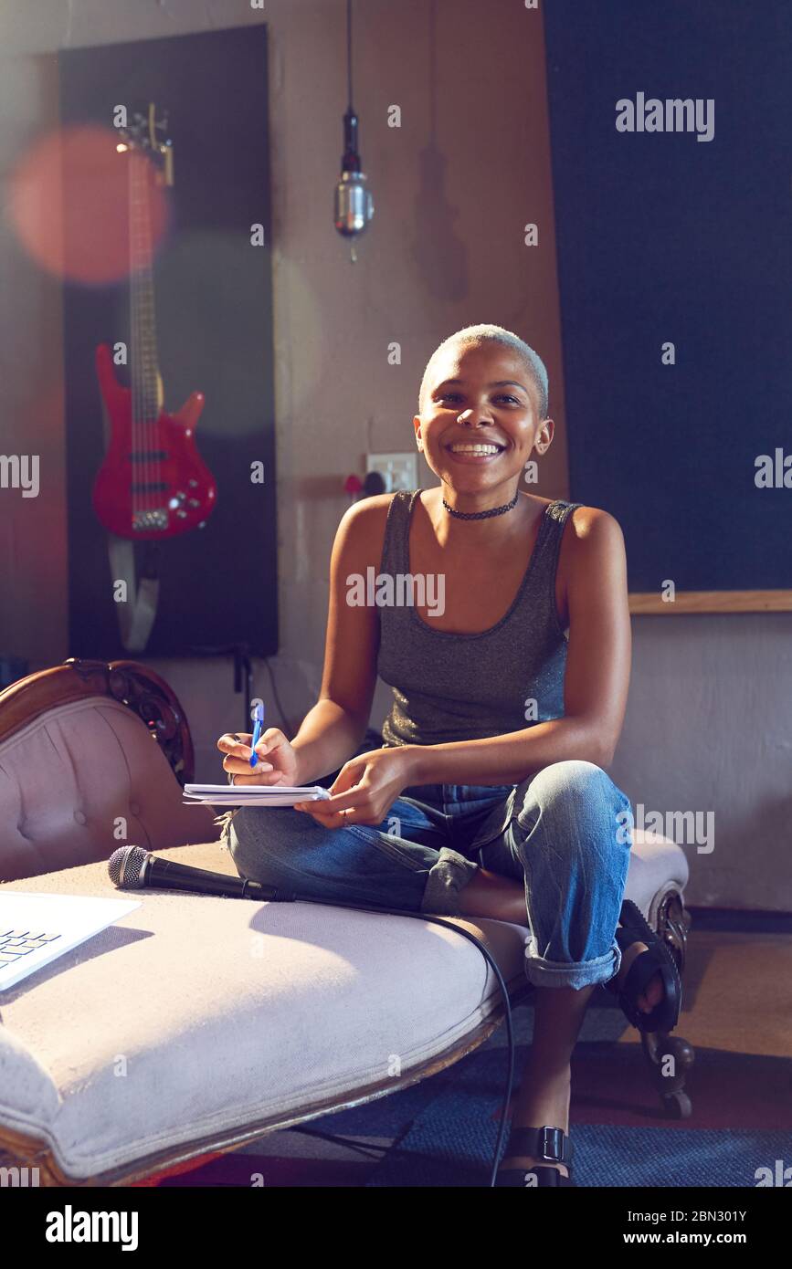 Portrait confident female musician song writing in recording studio ...