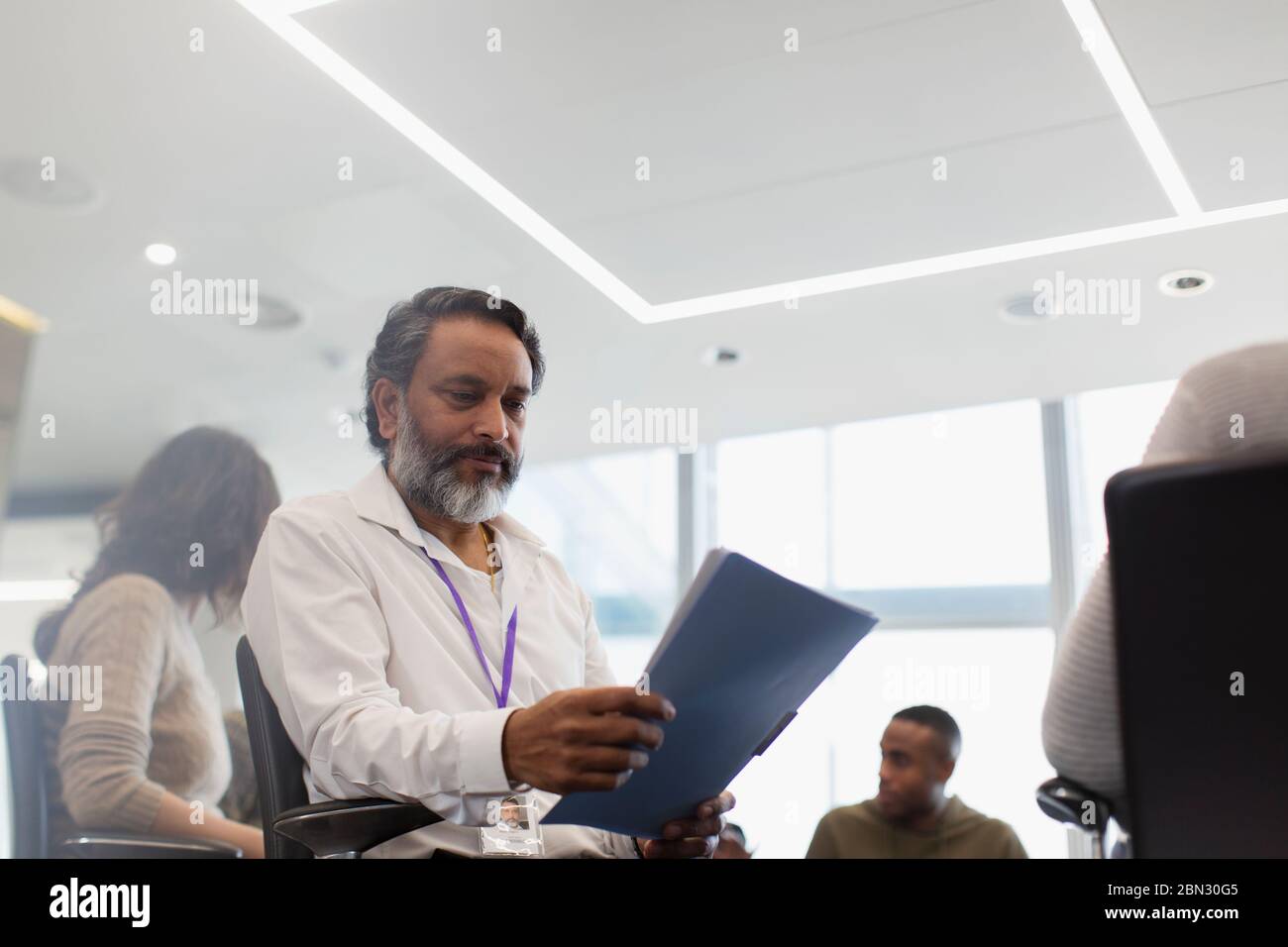 Focused businessman reading paperwork in meeting Stock Photo - Alamy