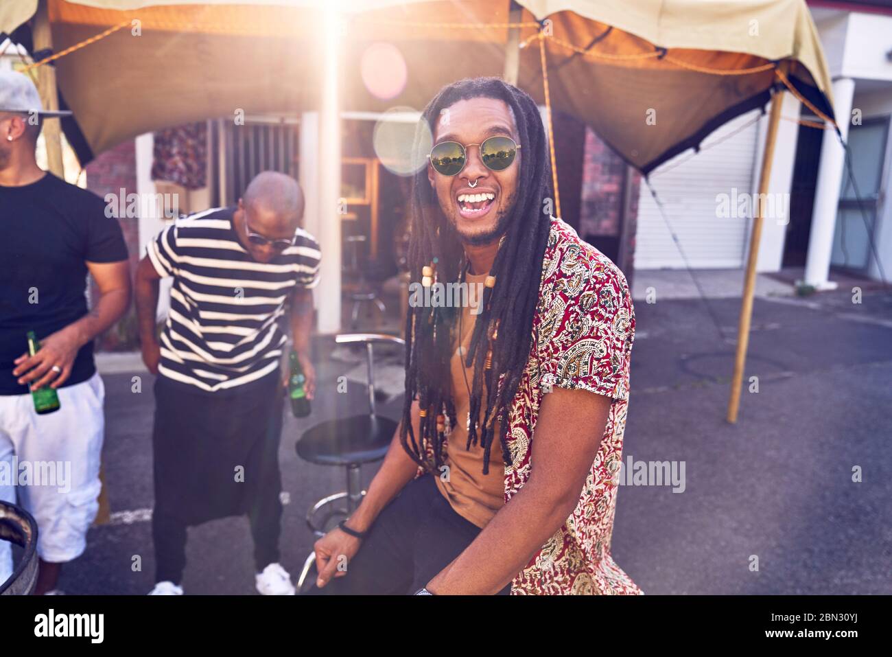 Portrait happy man hanging out with friends in sunny parking lot Stock ...