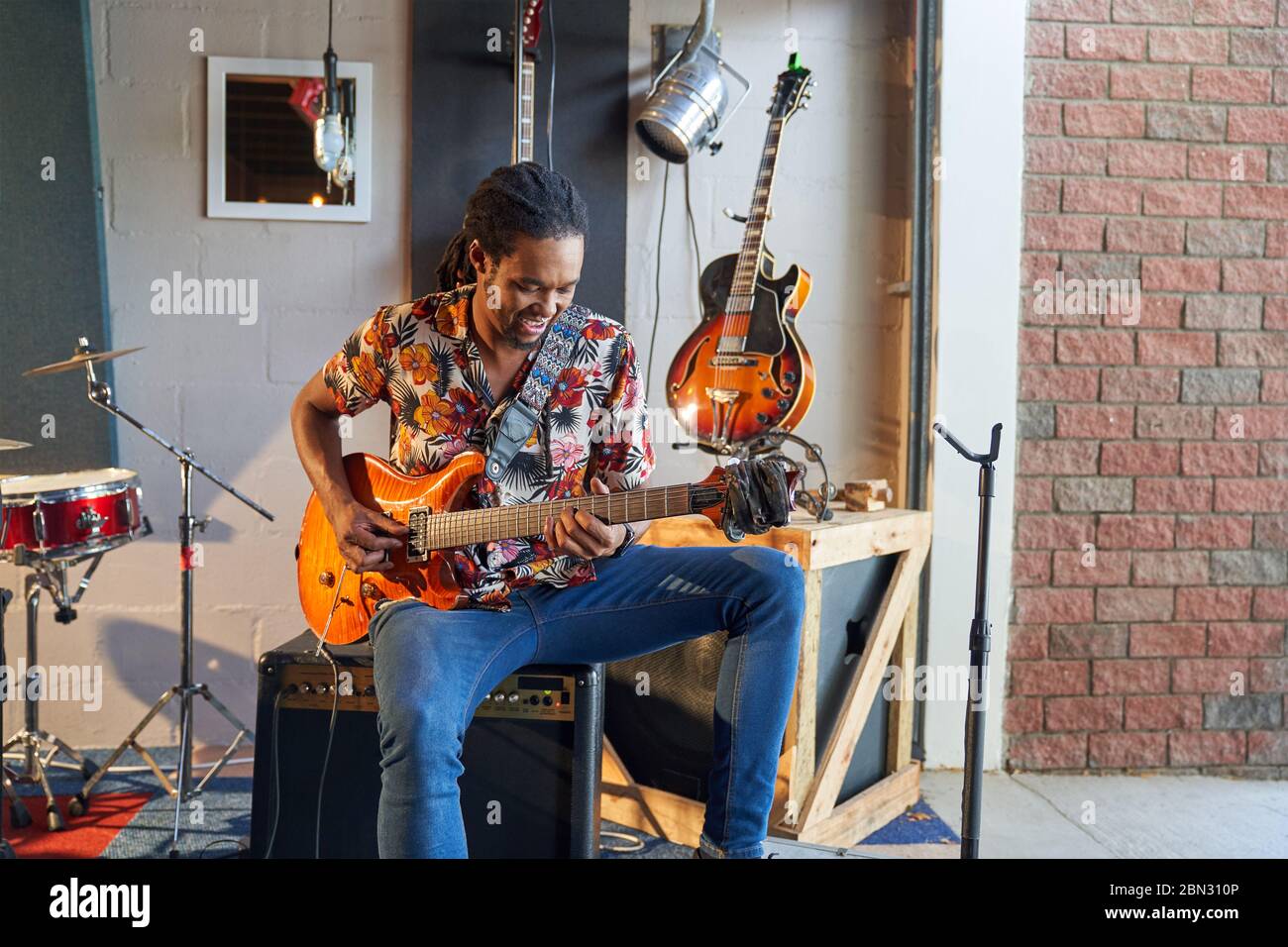 Male musician playing electric guitar in garage recording studio Stock ...