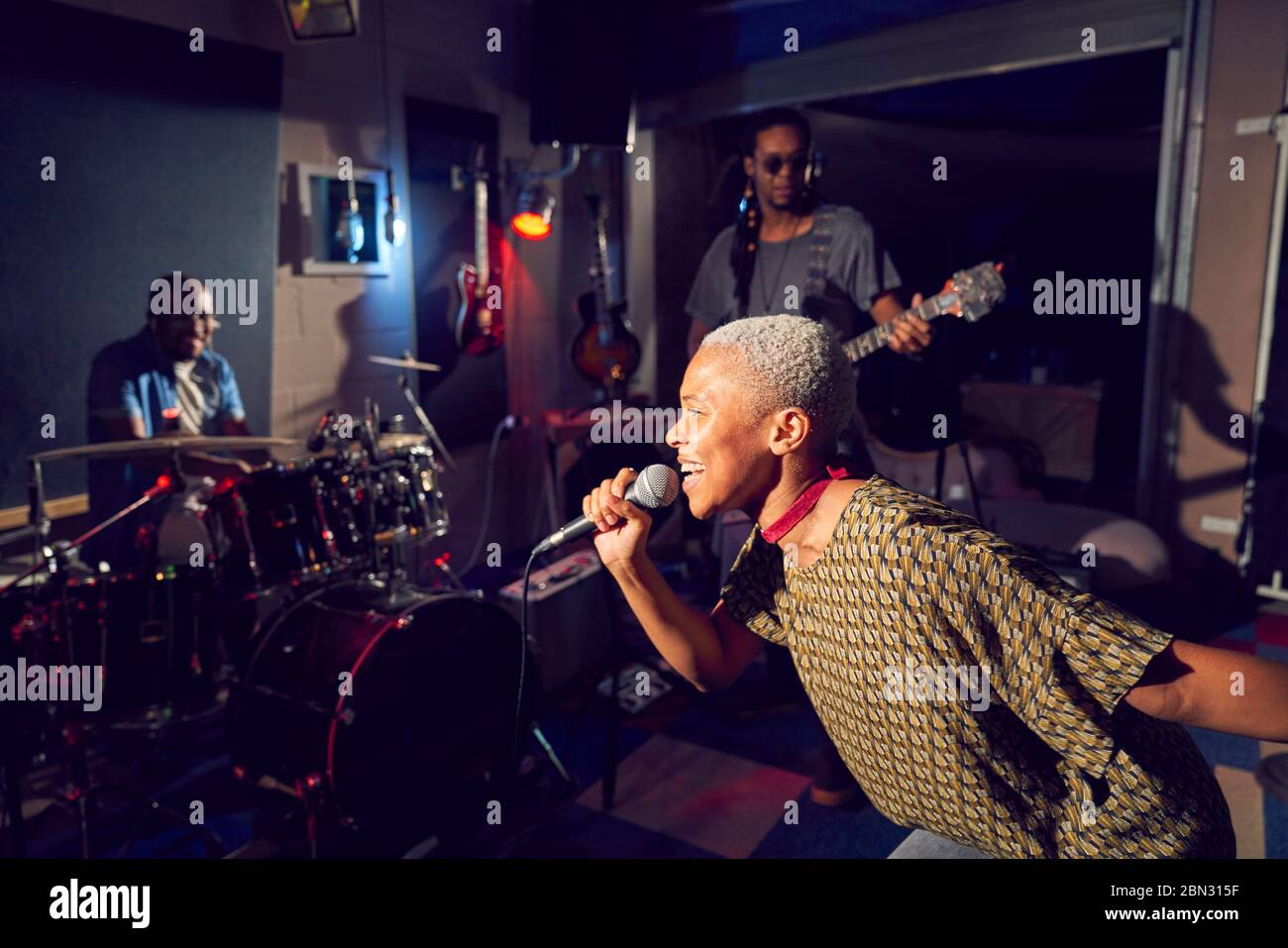 Female musician singing into microphone in recording studio Stock Photo ...