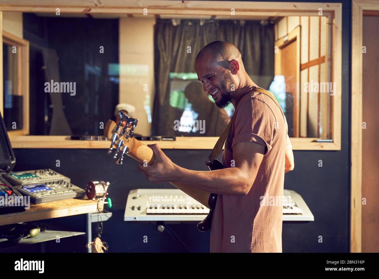 Happy male musician playing guitar in recording studio Stock Photo - Alamy