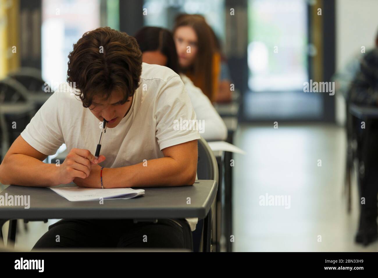 Focused high school boy student taking exam at desk in classroom Stock ...