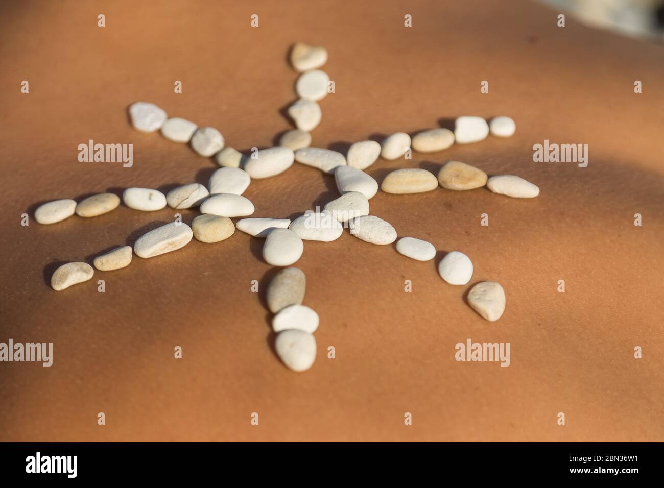 Sun made of small pebble stones on female back Stock Photo - Alamy