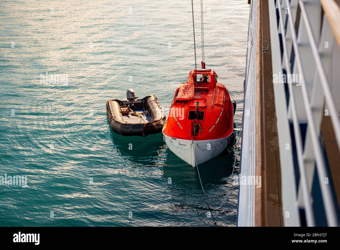 Lowering orange lifeboat to water in Arctic waters, Svalbard. Abandon ...