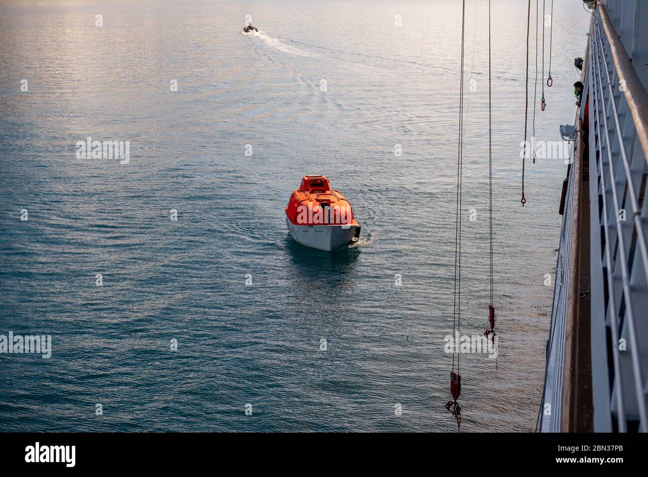 Maneuvering orange lifeboat in water in Arctic waters, Svalbard ...