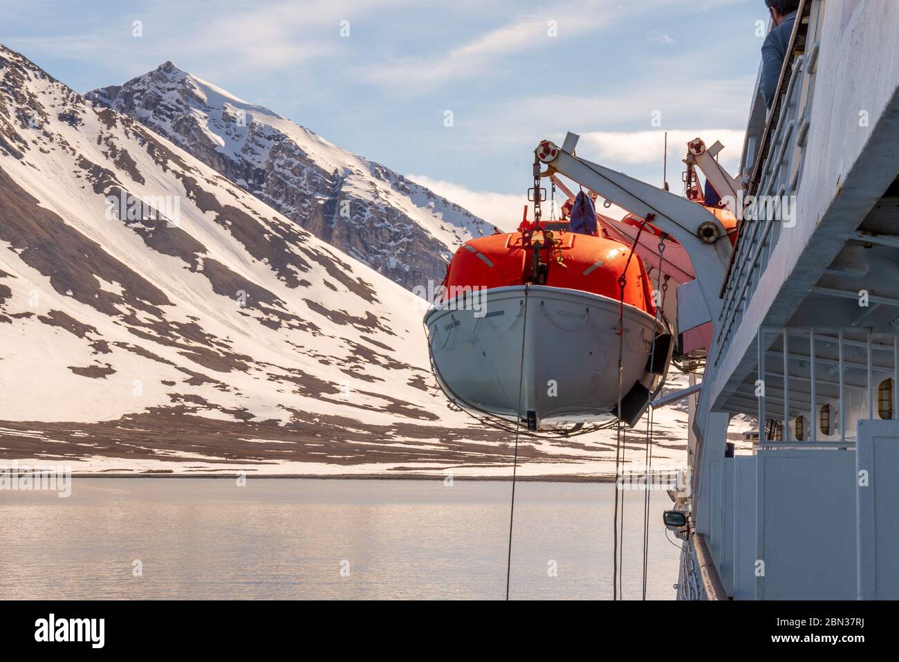 Lowering orange lifeboat to water in Arctic waters, Svalbard. Abandon ...