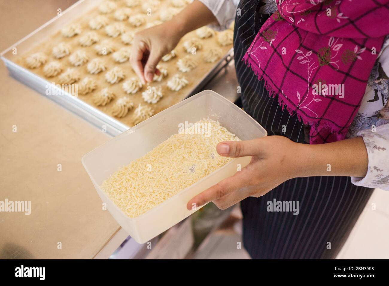 hand put a cheese topping on a cake. semprit traditional cake. kue ...