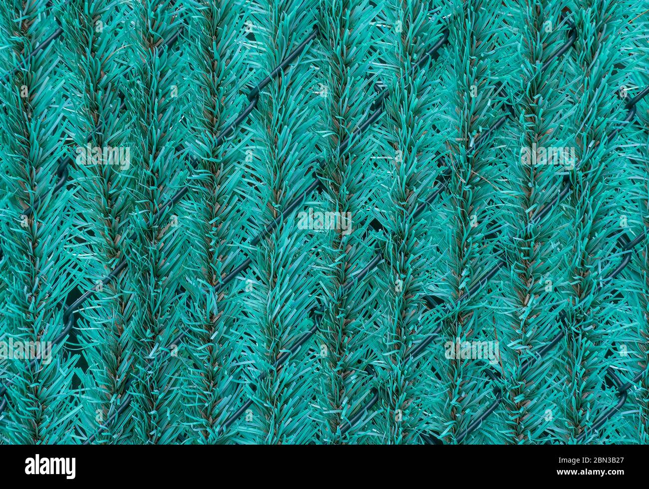 background of fake evergreen woven through a green chain link fence ...