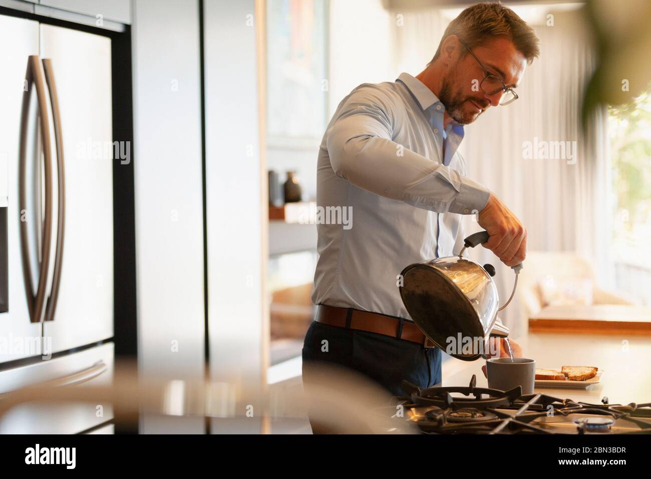 Businessman making tea in morning kitchen Stock Photo - Alamy