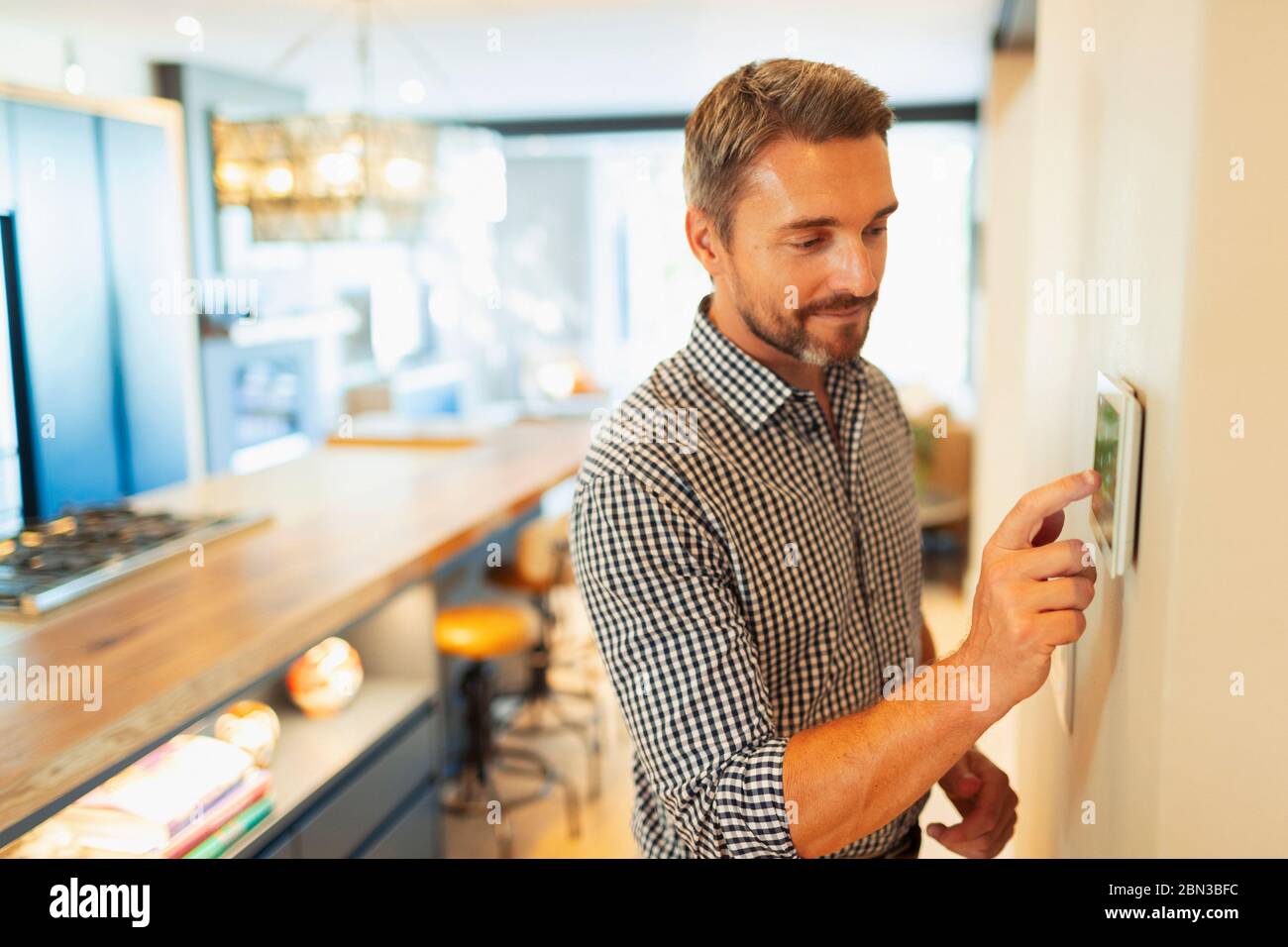 Man adjusting digital home automation thermostat Stock Photo - Alamy