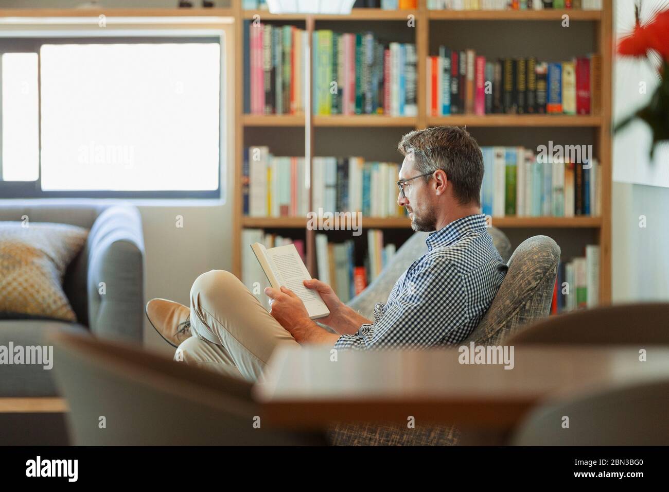 Man relaxing, reading book in living room Stock Photo - Alamy