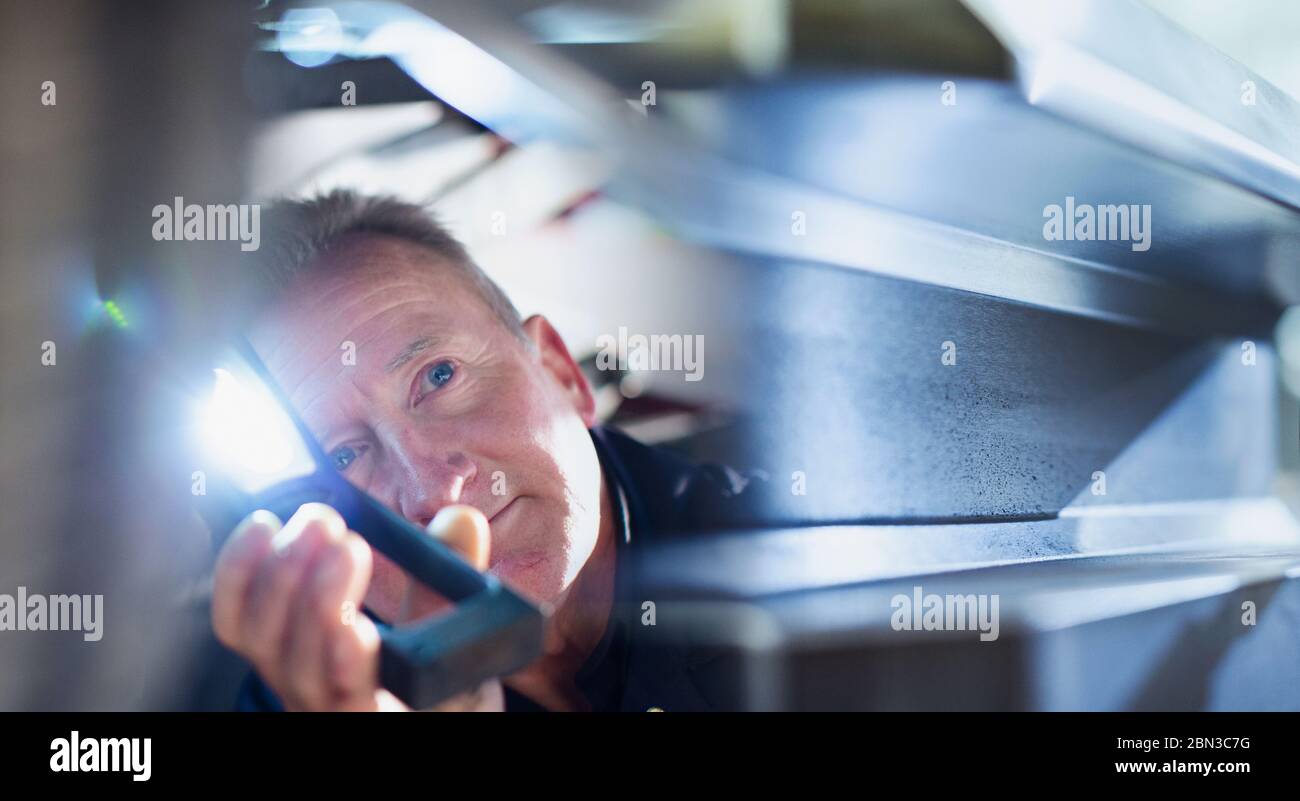 Male mechanic with flashlight working under car Stock Photo - Alamy