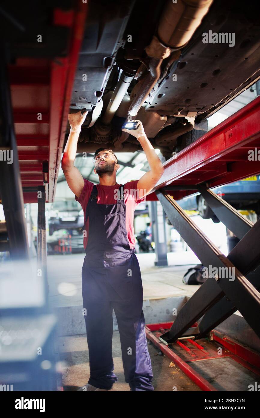 Male mechanic working under car in auto repair shop Stock Photo - Alamy