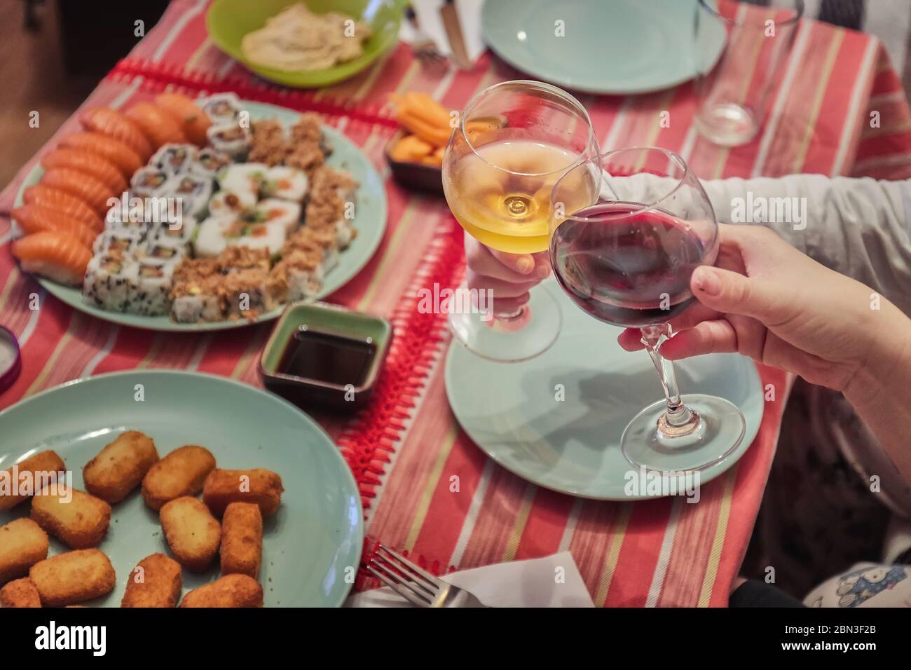 Two persons cheers in a table dinner with sushi and fried cheese Stock ...