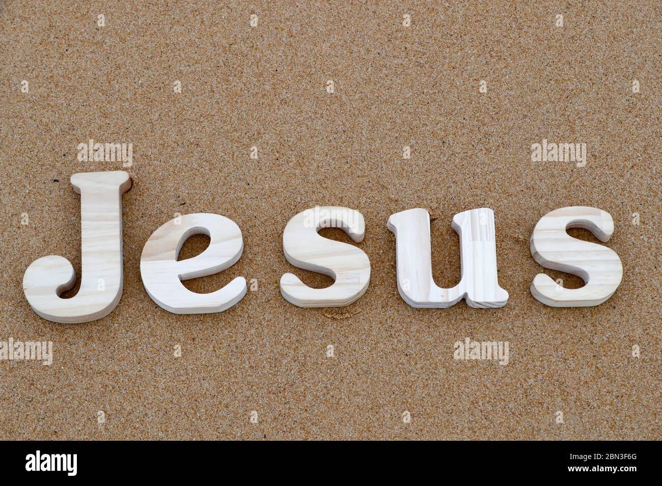 Wooden letters forming the word Jesus on a background of beach sand ...