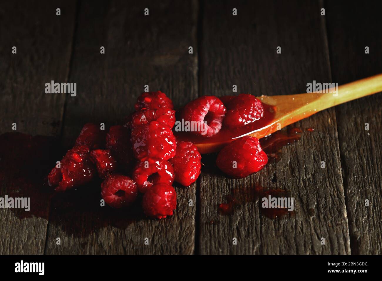 Raspberry jam and wooden spoon Stock Photo - Alamy