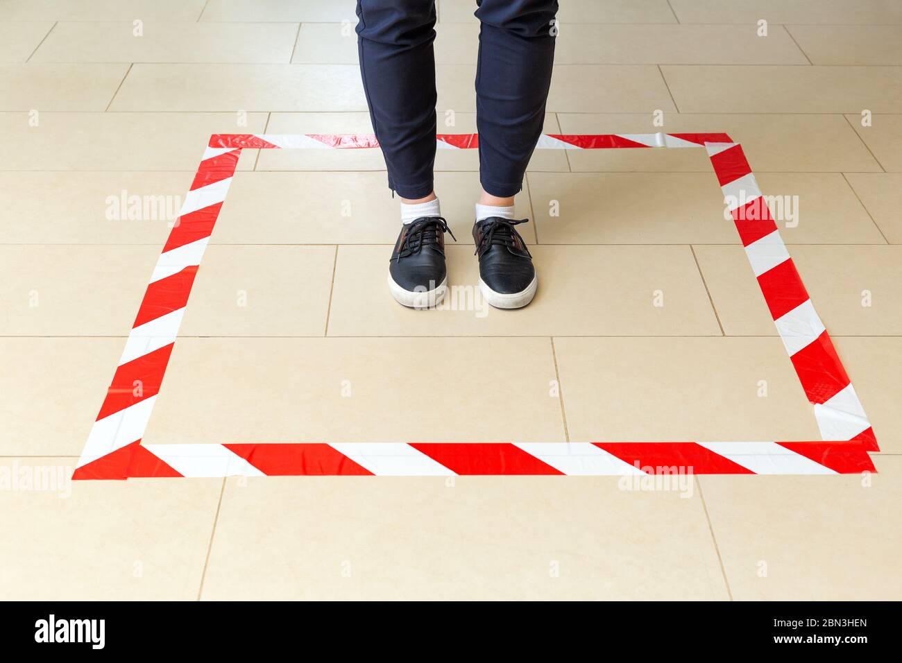 Woman stand in line keeping social distance, standing behind a warning ...