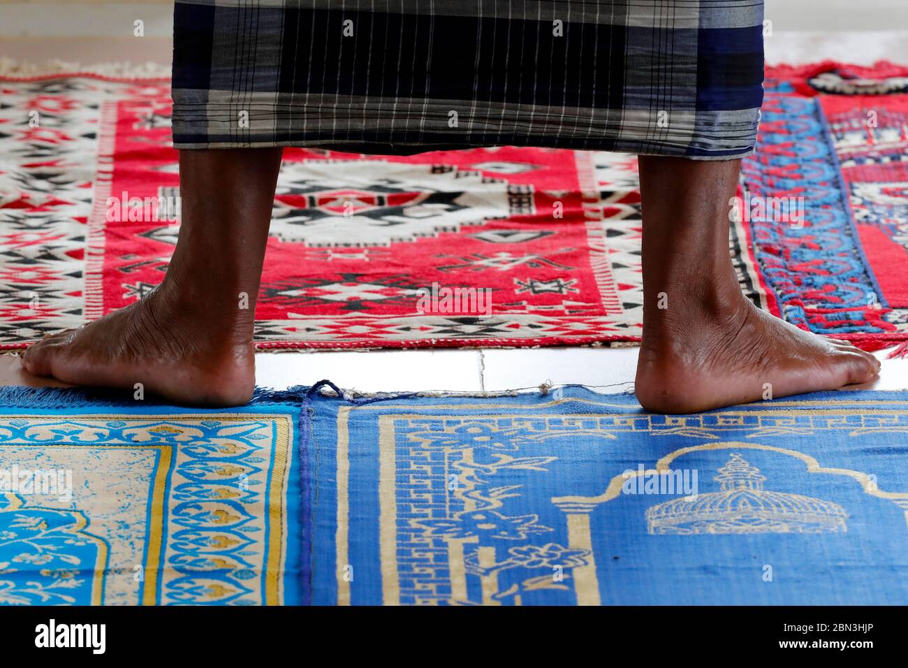 Muslim man praying in mosque. Close-up on feet on prayer mat. Kep ...