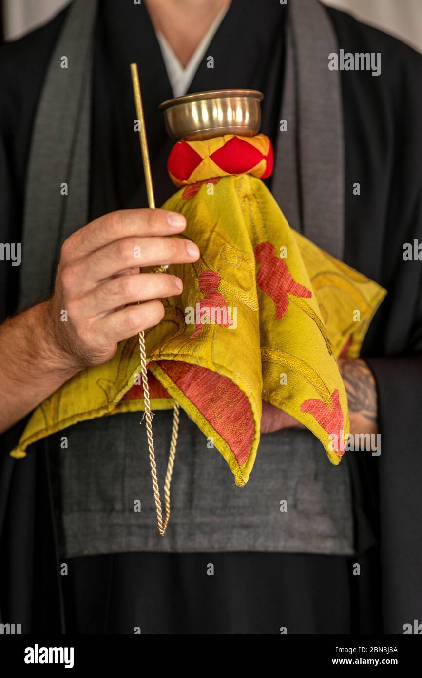 Zen monk sounding a hand-bell called inkin during a buddhist ceremony ...