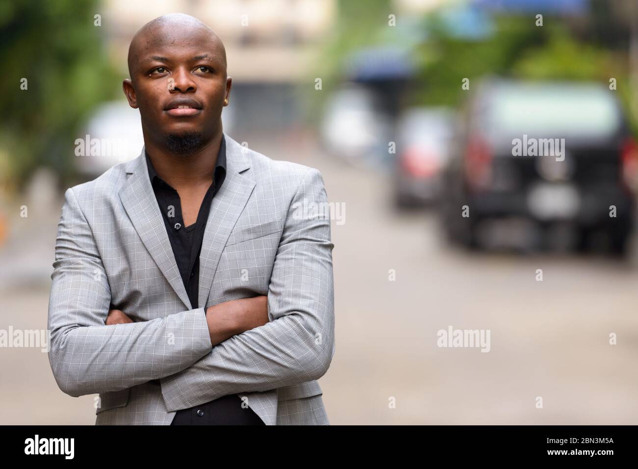 Happy young handsome bald African businessman thinking outdoors Stock ...