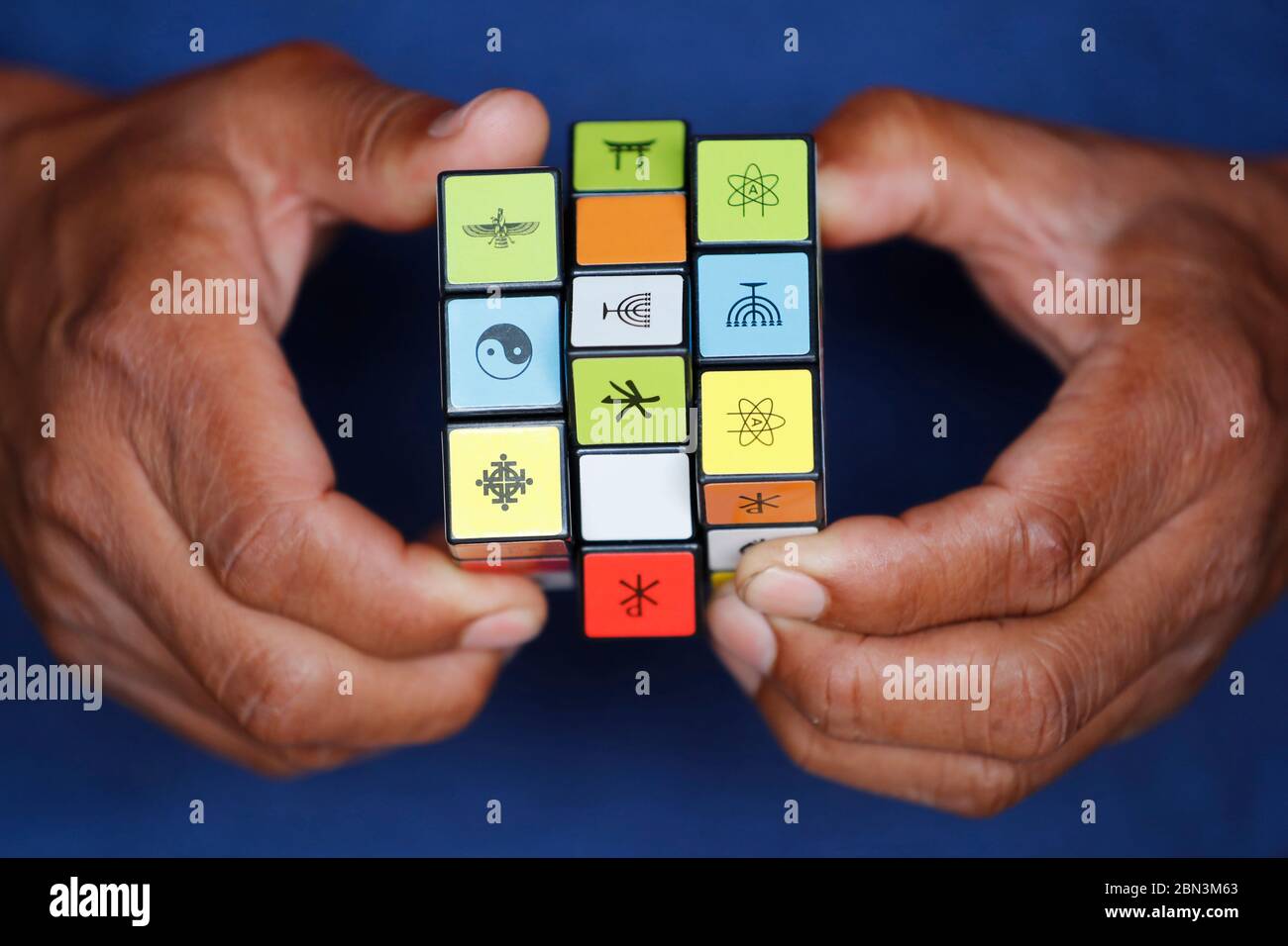 African man with a Rubik's cube with religious symbols. Interreligious ...