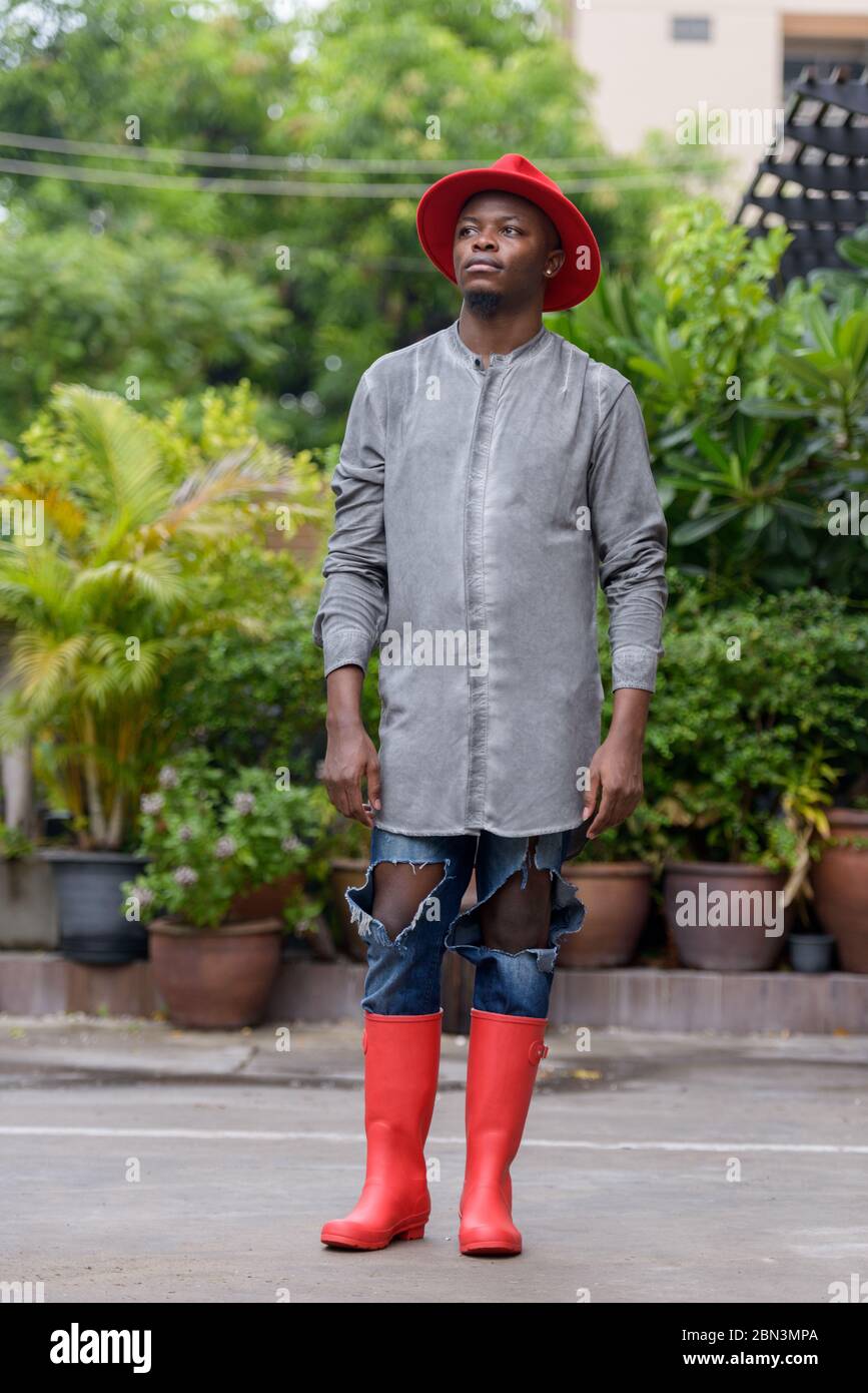 Full body shot of young handsome African man thinking outdoors Stock ...