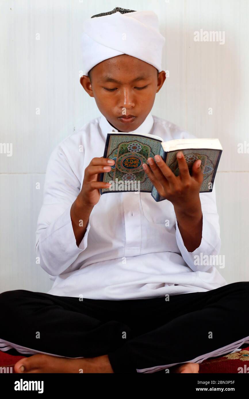 Masjid Ar-Rohmah mosque. Muslim boy reading an Arabic Holy Quran (Koran ...